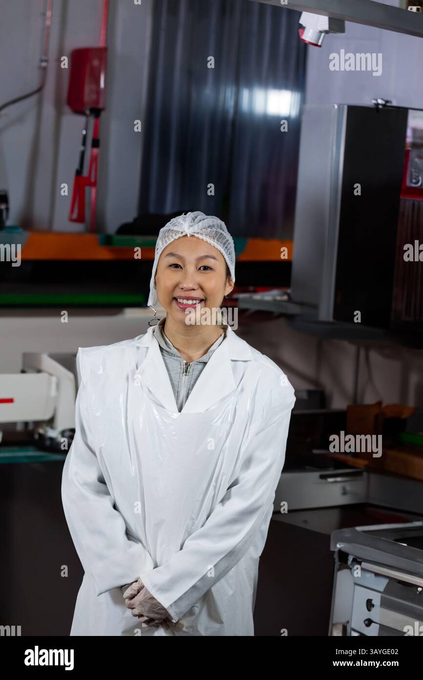 Asian woman standing and smiling inside food processing facility, with ...