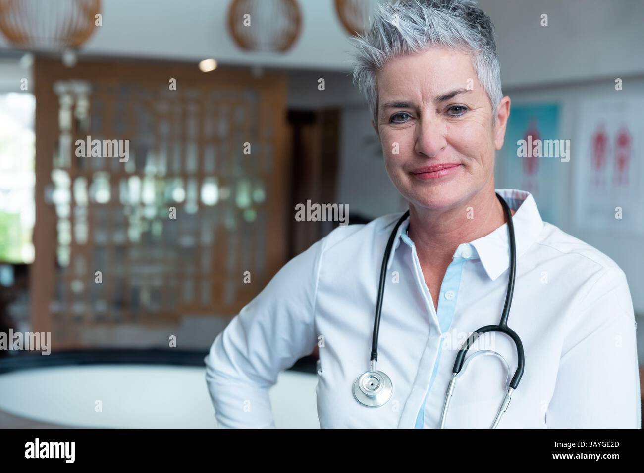 Senior female doctor greeting patients at hospital reception desk, wearing stethoscope, copy ...
