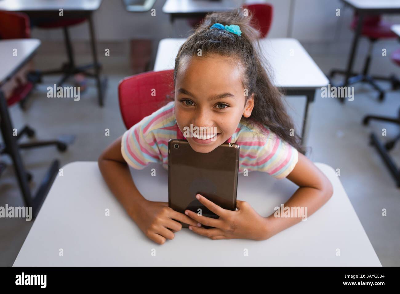 Female child leaning forward on white desk in elementary classroom with ...