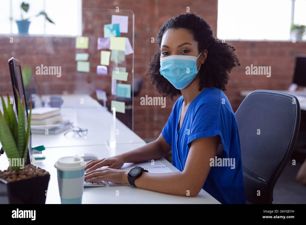 bi-racial young adult woman typing on keyboard at office desk, among ...