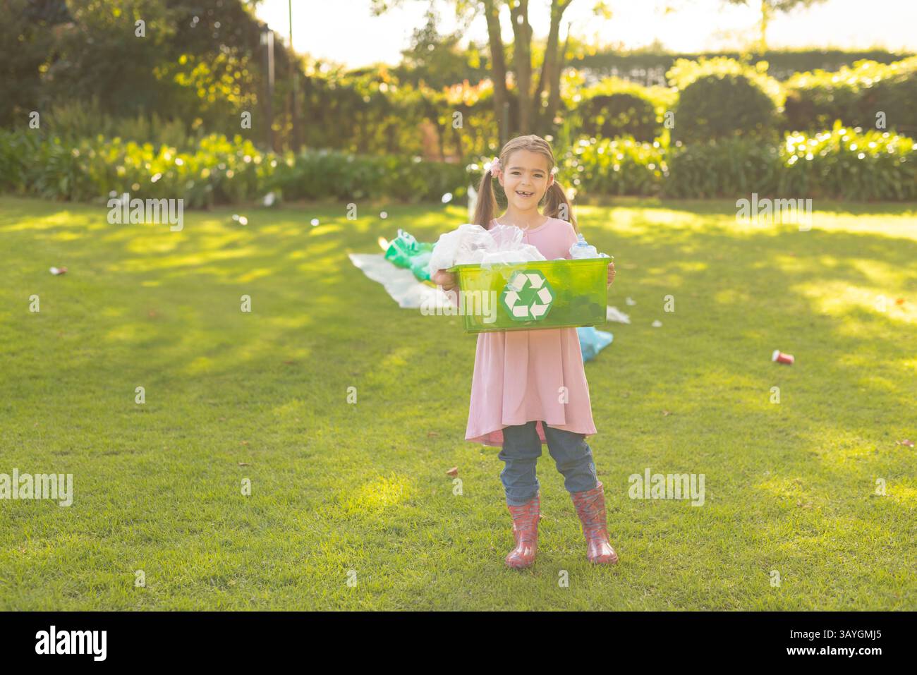 Girl holding green recycling crate filled with plastic bottles and ...