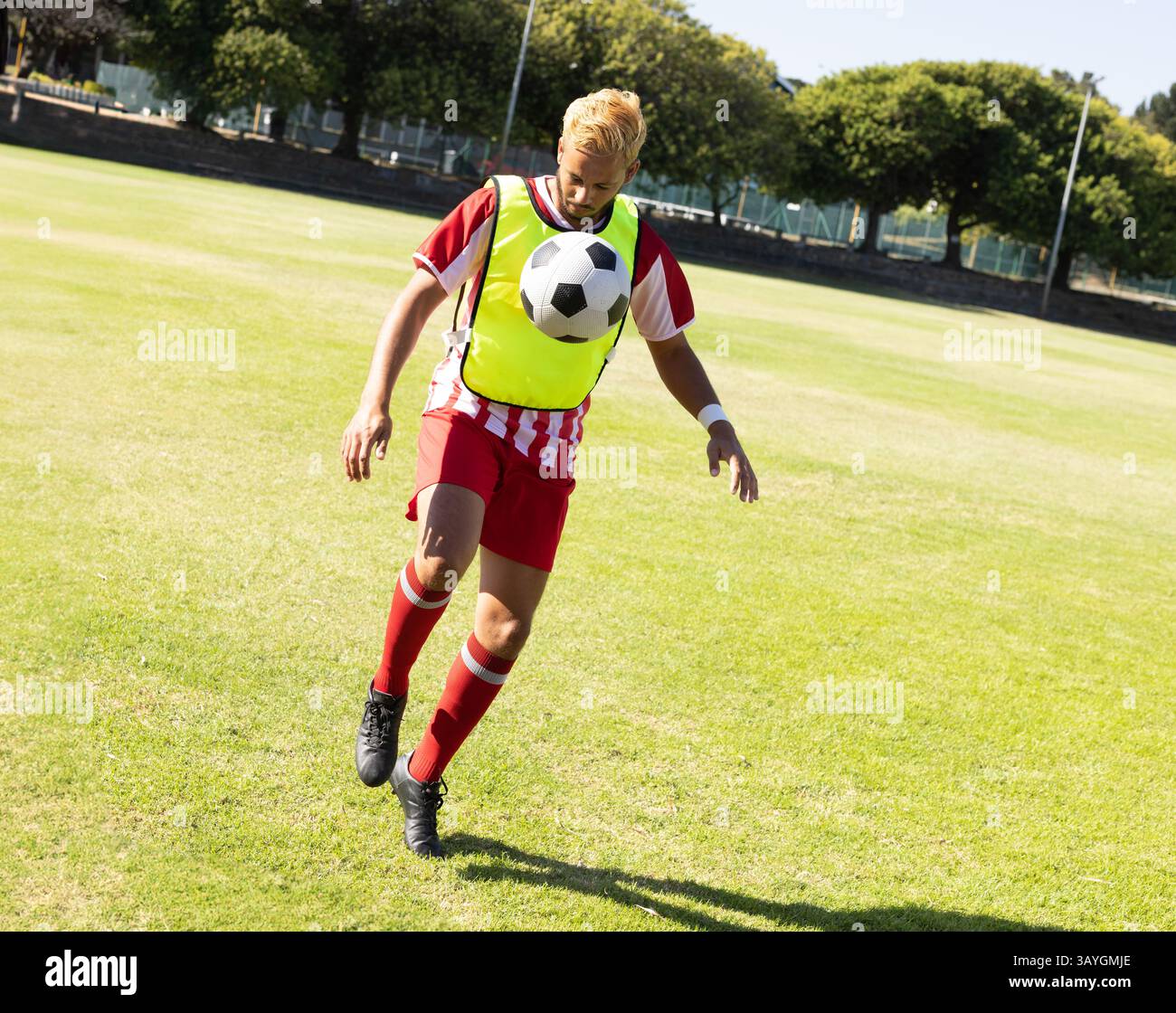 bi-racial male soccer player controlling ball mid-air on grass field ...