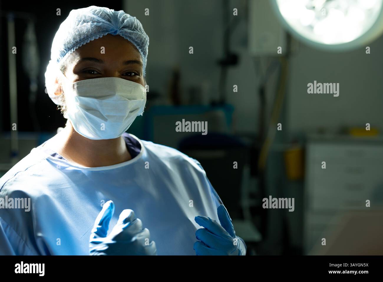 Diverse female surgeon adjusting latex gloves in hospital operating ...