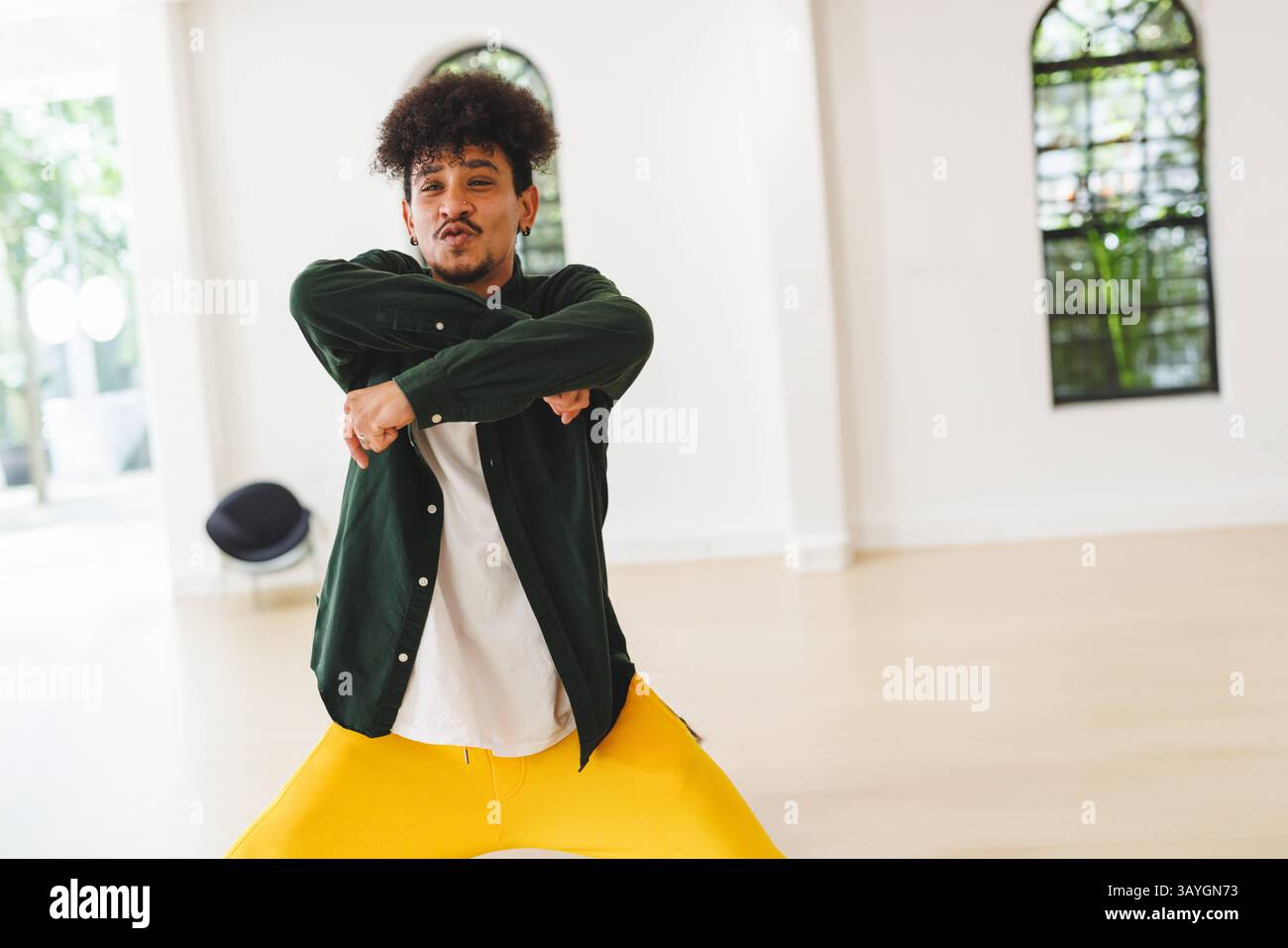 Man dancing in modern dance studio with glass doors, arched window and ...