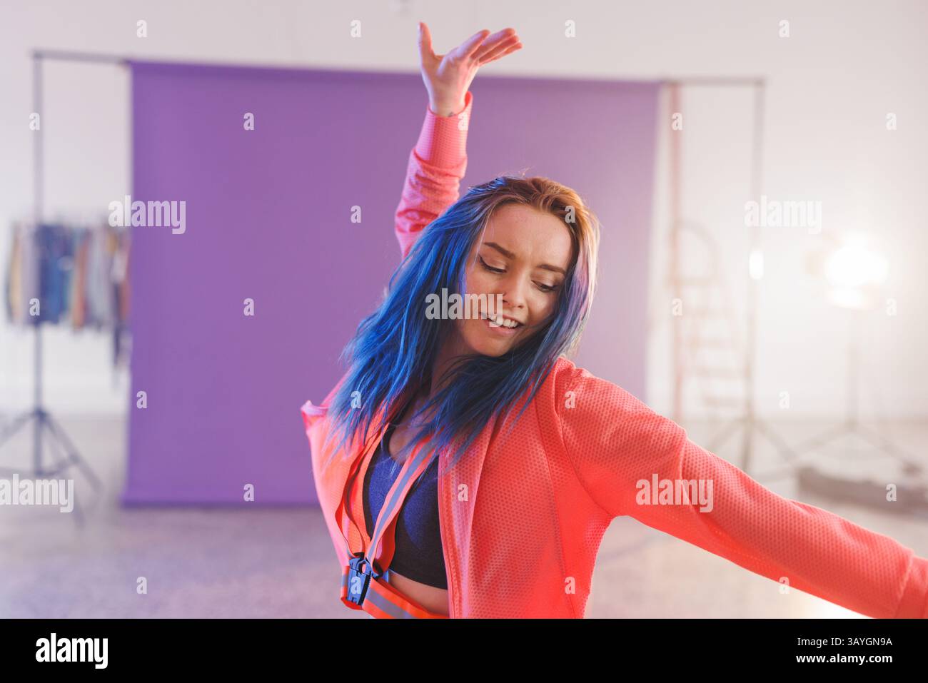 Non-binary young adult dancing in photography studio with purple ...
