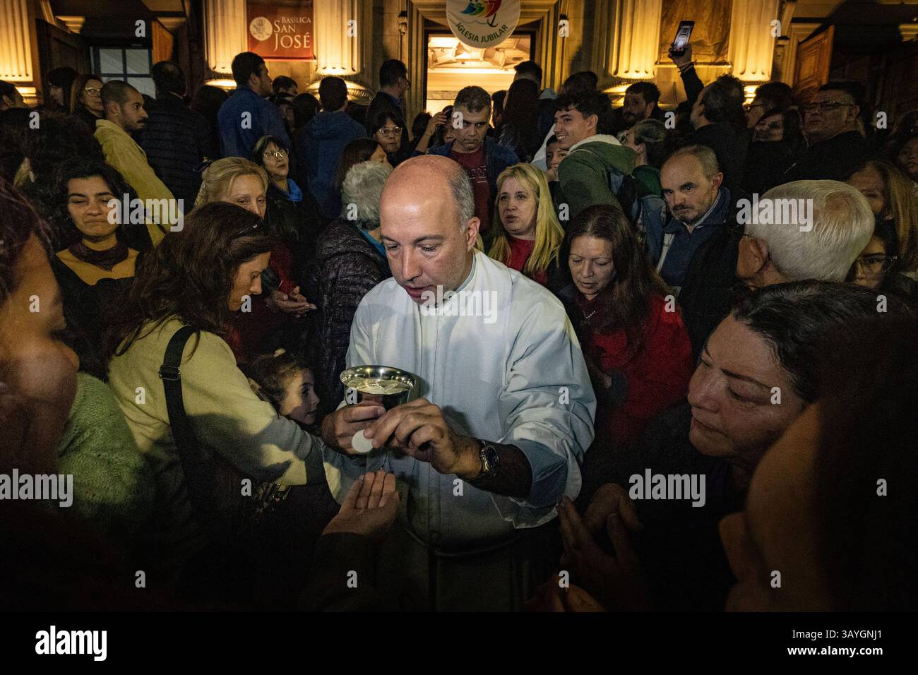 One of the priests gives communion to the faithful gathered outside the ...