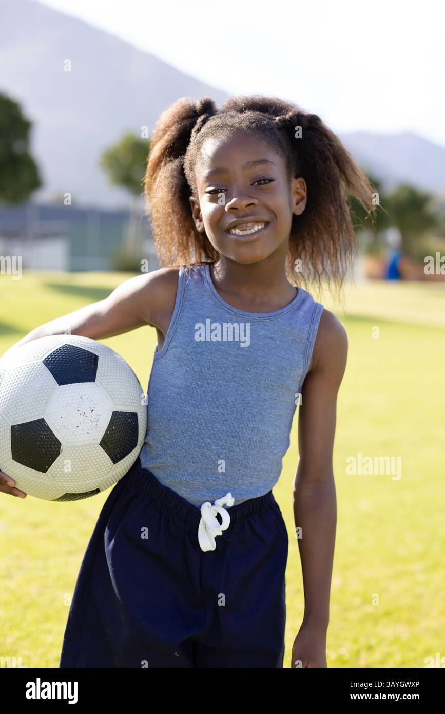 African American child holding soccer ball on grassy sports field ...