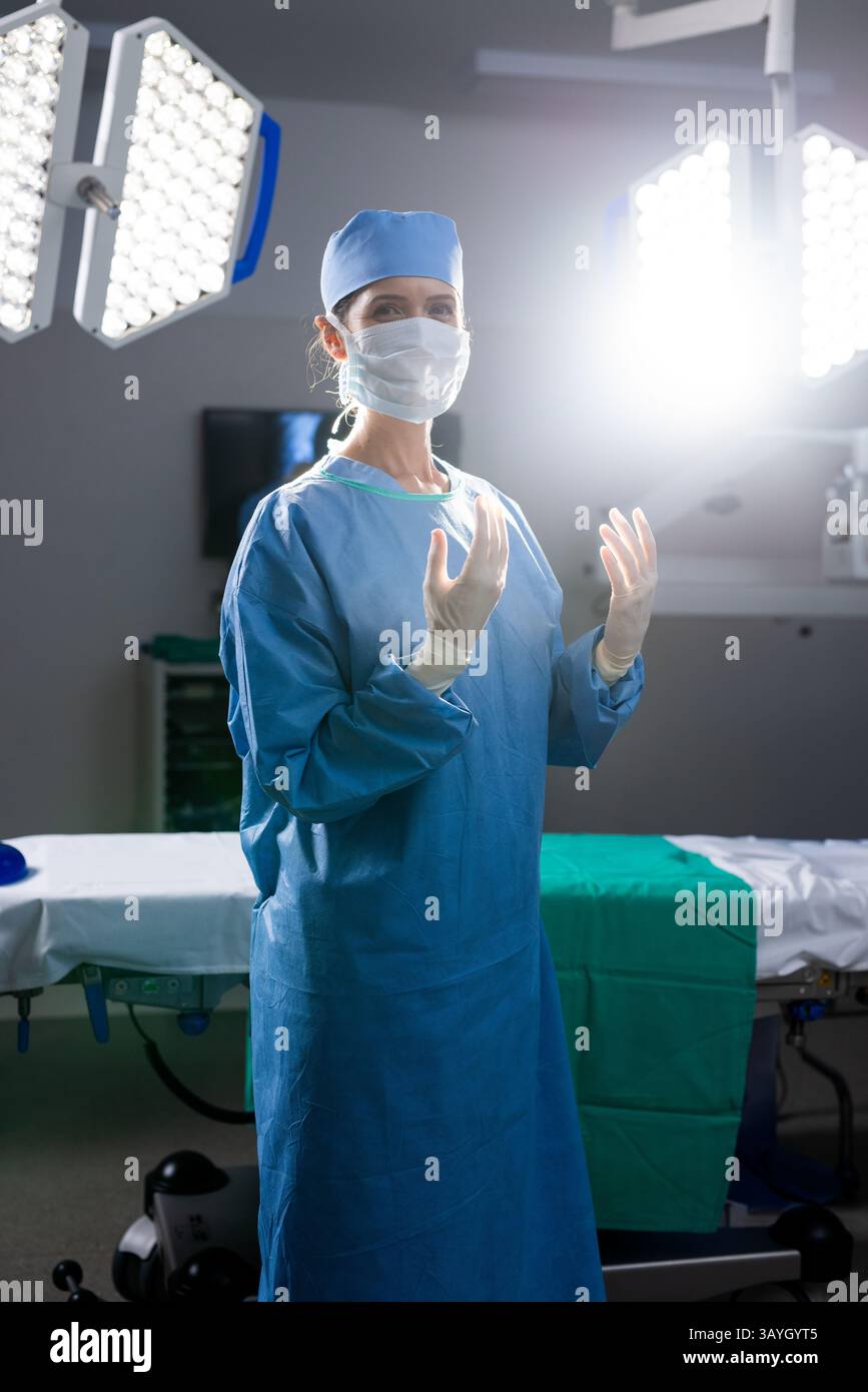 Female surgeon standing in operating room under overhead LED lights ...