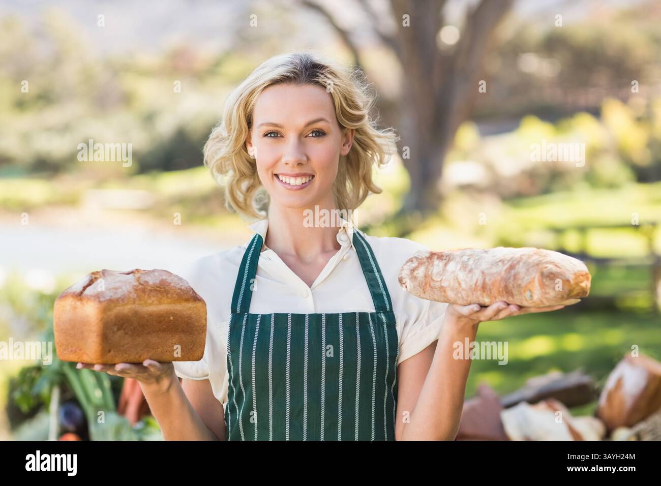 woman holding sandwich loaf and baguette at outdoor farmers market ...