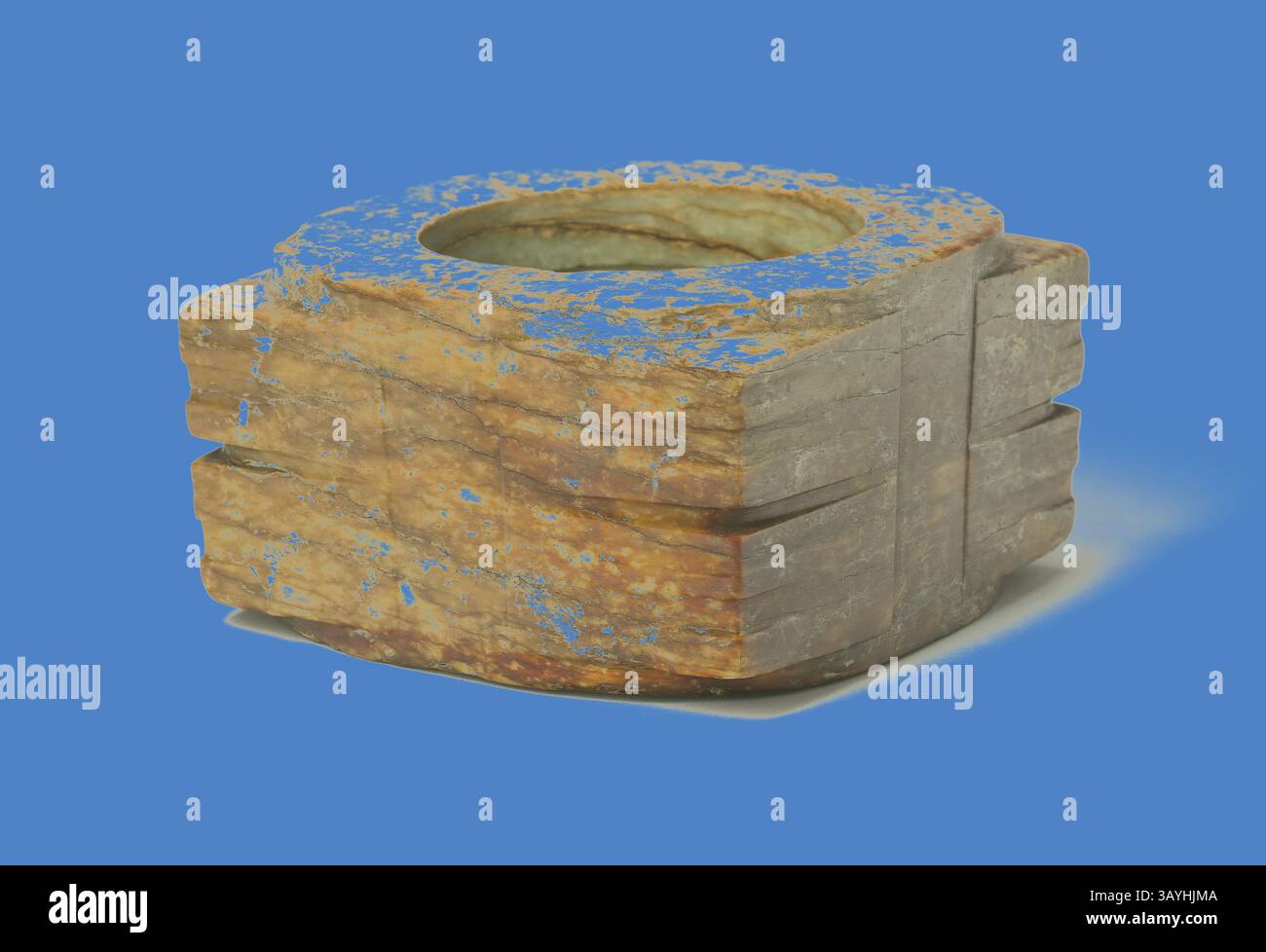 A square, textured stone object with a hollow center, featuring layers ...