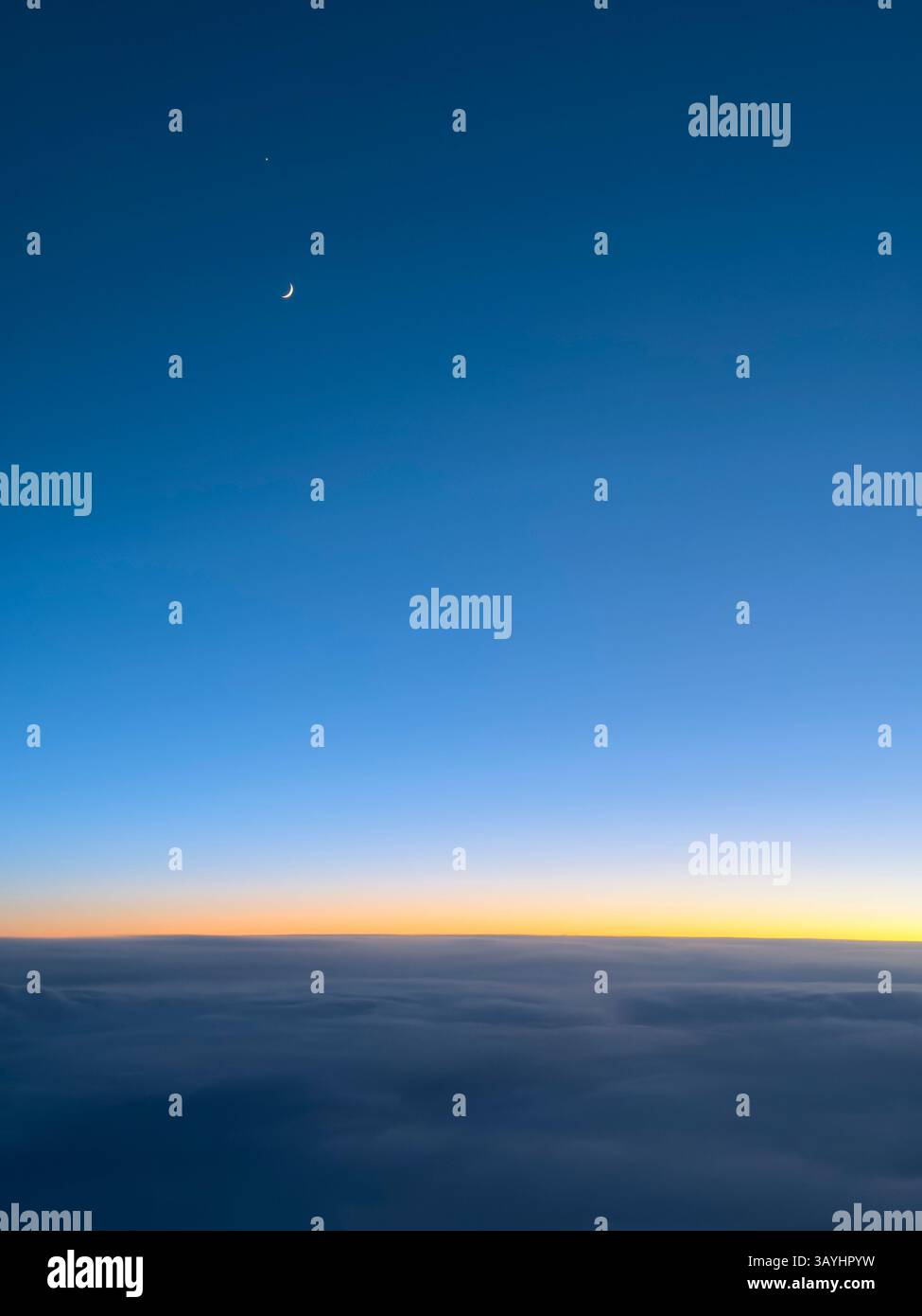 Crescent moon in deep blue sky at sunset viewed through airplane window ...