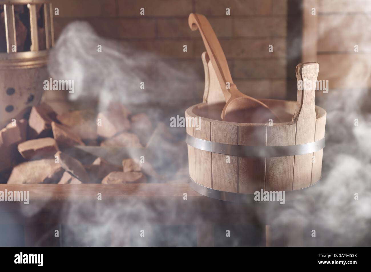 Bucket, ladle and stove with hot rocks surrounded by steam in sauna ...