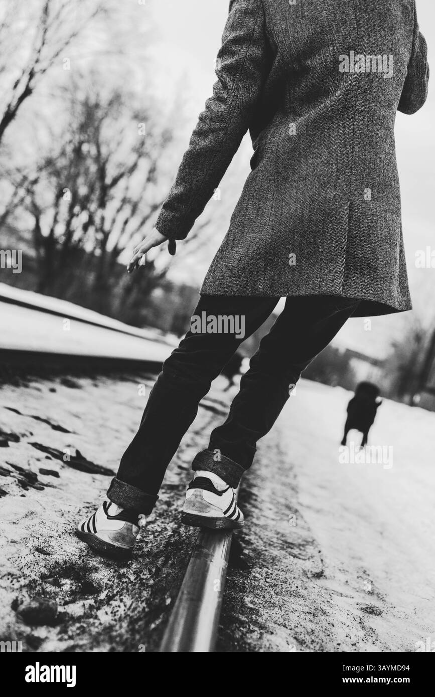 Black and white photo of a man walking along railroad tracks with his ...