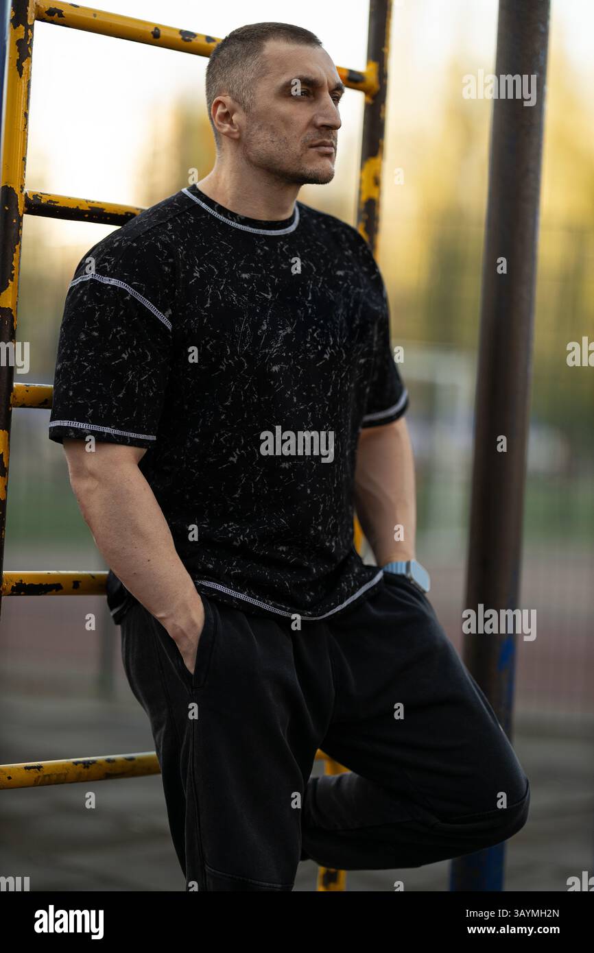 man closely cropped hair stands confidently against yellow playground ...