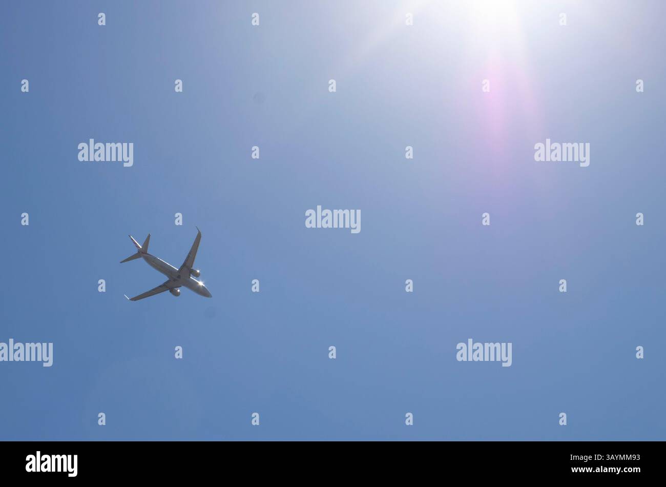 white airplane flying across blue sky Stock Photo - Alamy