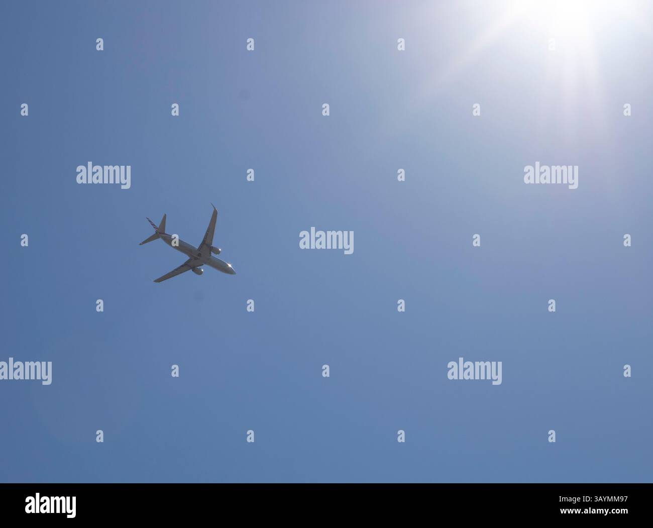 white airplane flying across blue sky Stock Photo - Alamy