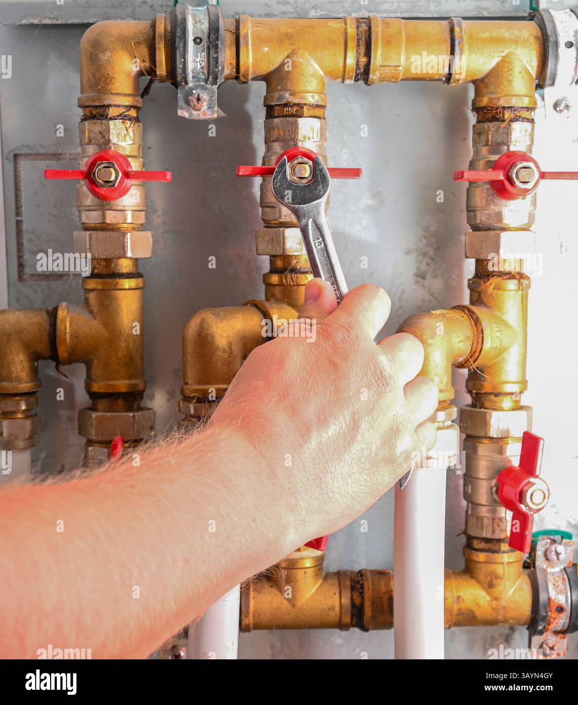 Plumber tightening water pipes with adjustable wrench during ...