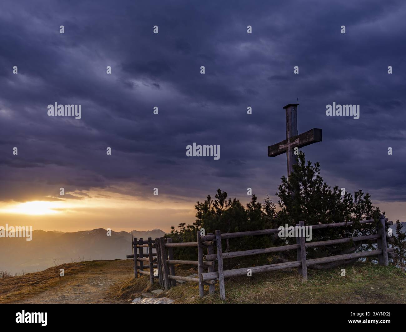Summit cross on the Rossfeld under a dramatically overcast sky, the sun ...