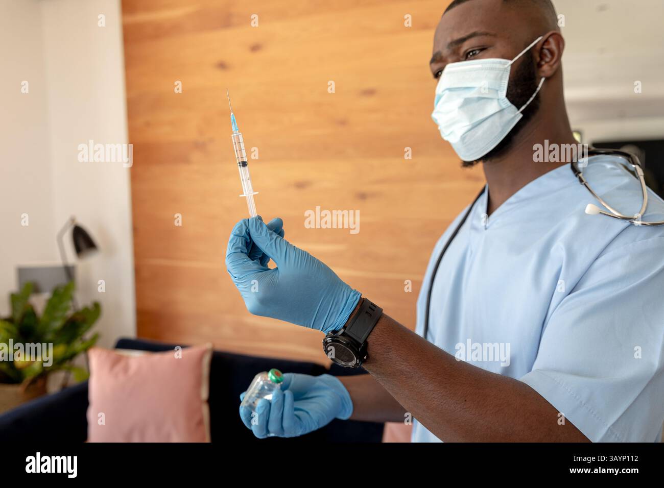 African American male clinician inspecting syringe and vial at clinic ...