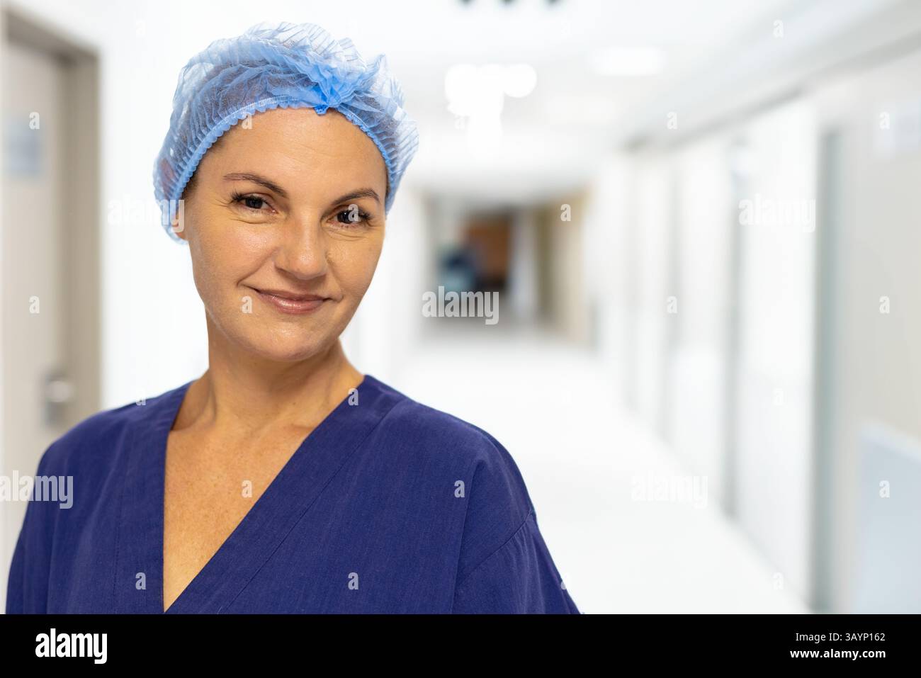 Female nurse standing and smiling in hospital corridor, wearing navy ...