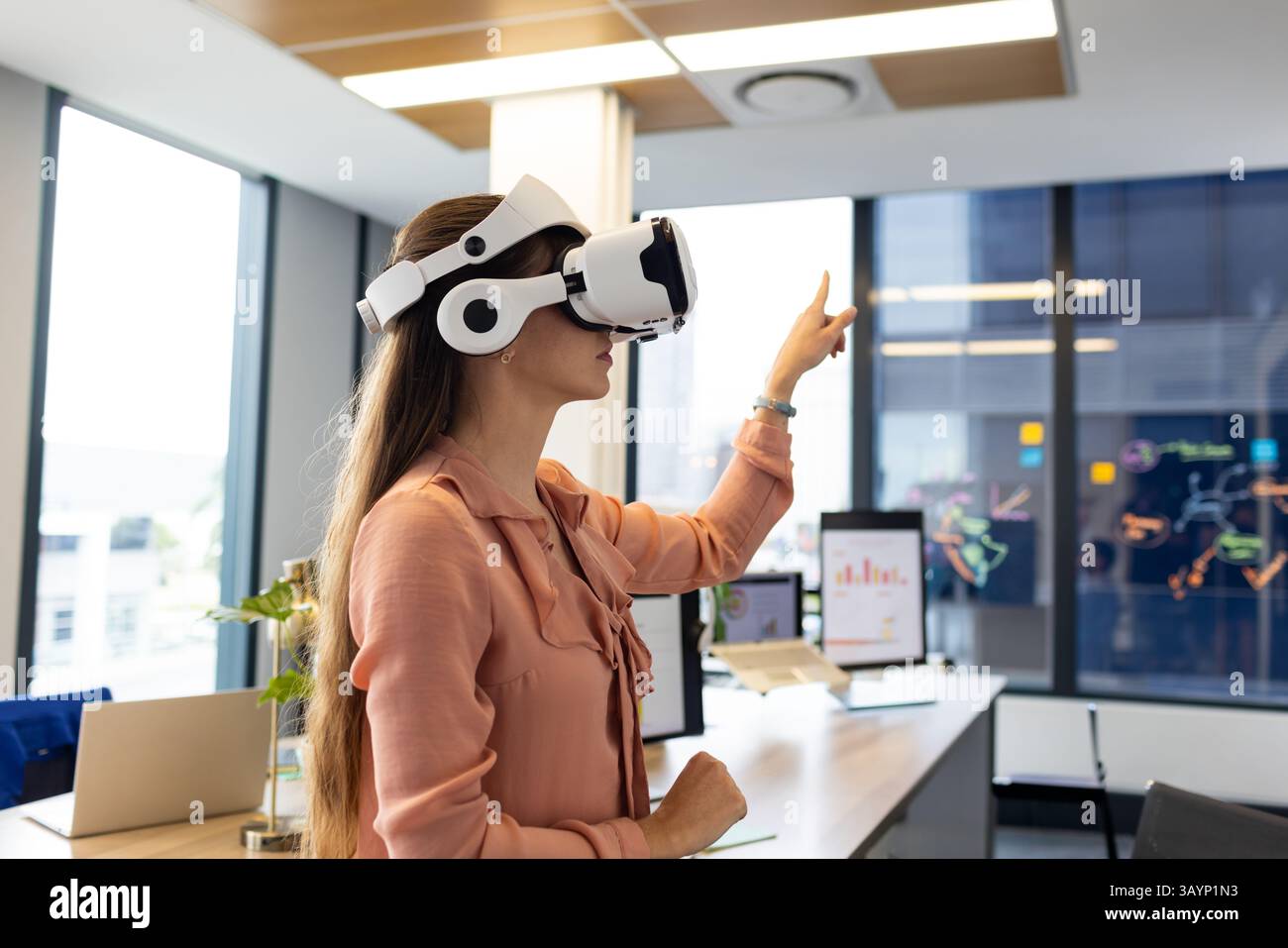 Mid-adult woman wearing VR headset reaching toward virtual interface at ...
