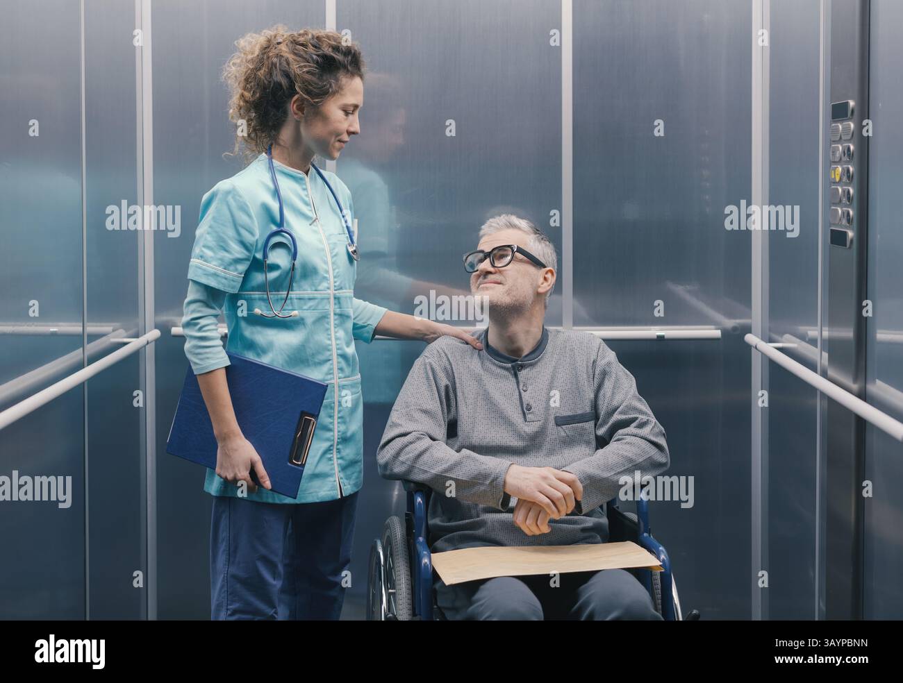 Caring female doctor assisting a male patient in wheelchair in the ...