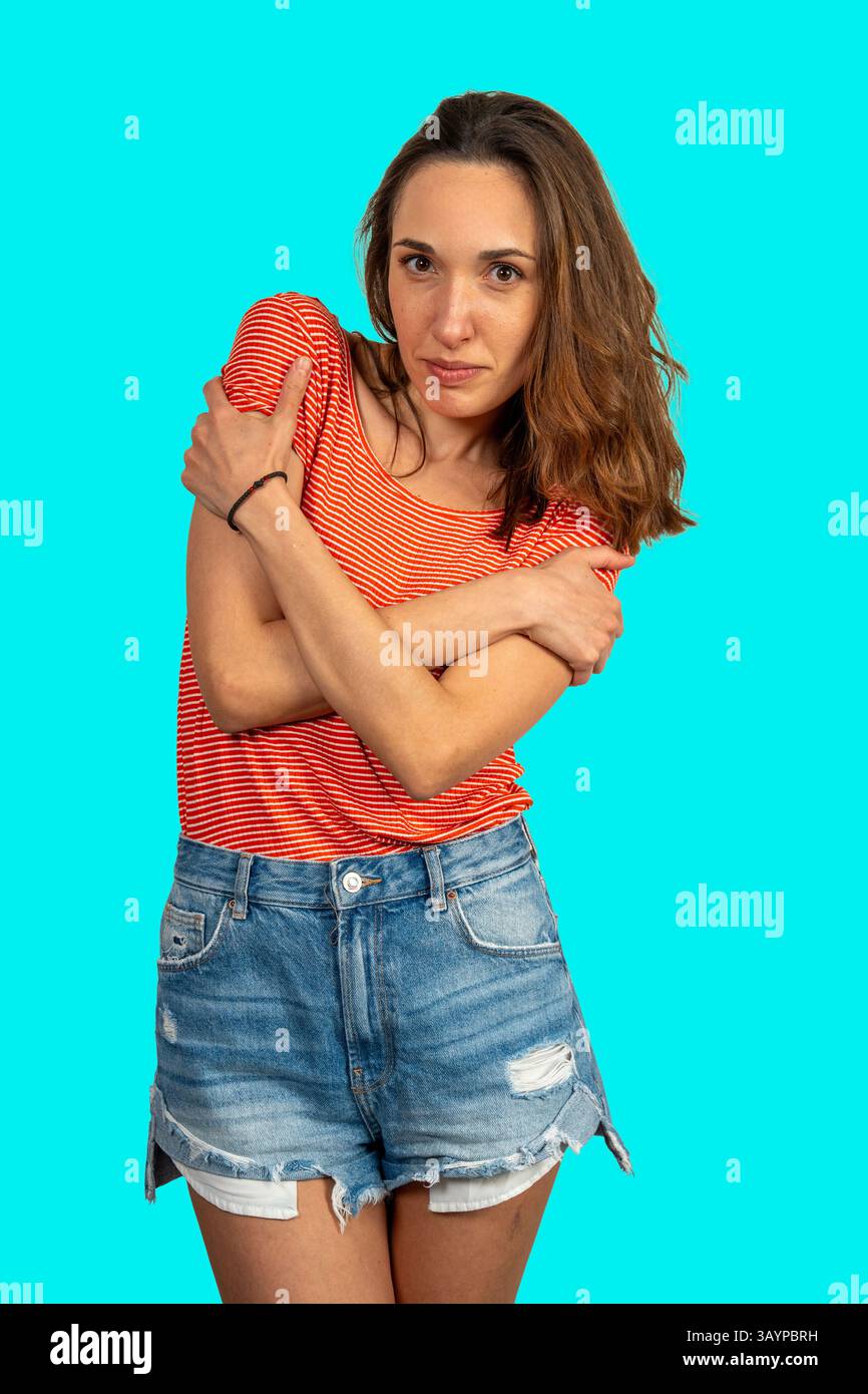 Studio shot of a young woman hugging herself, feeling insecure and ...