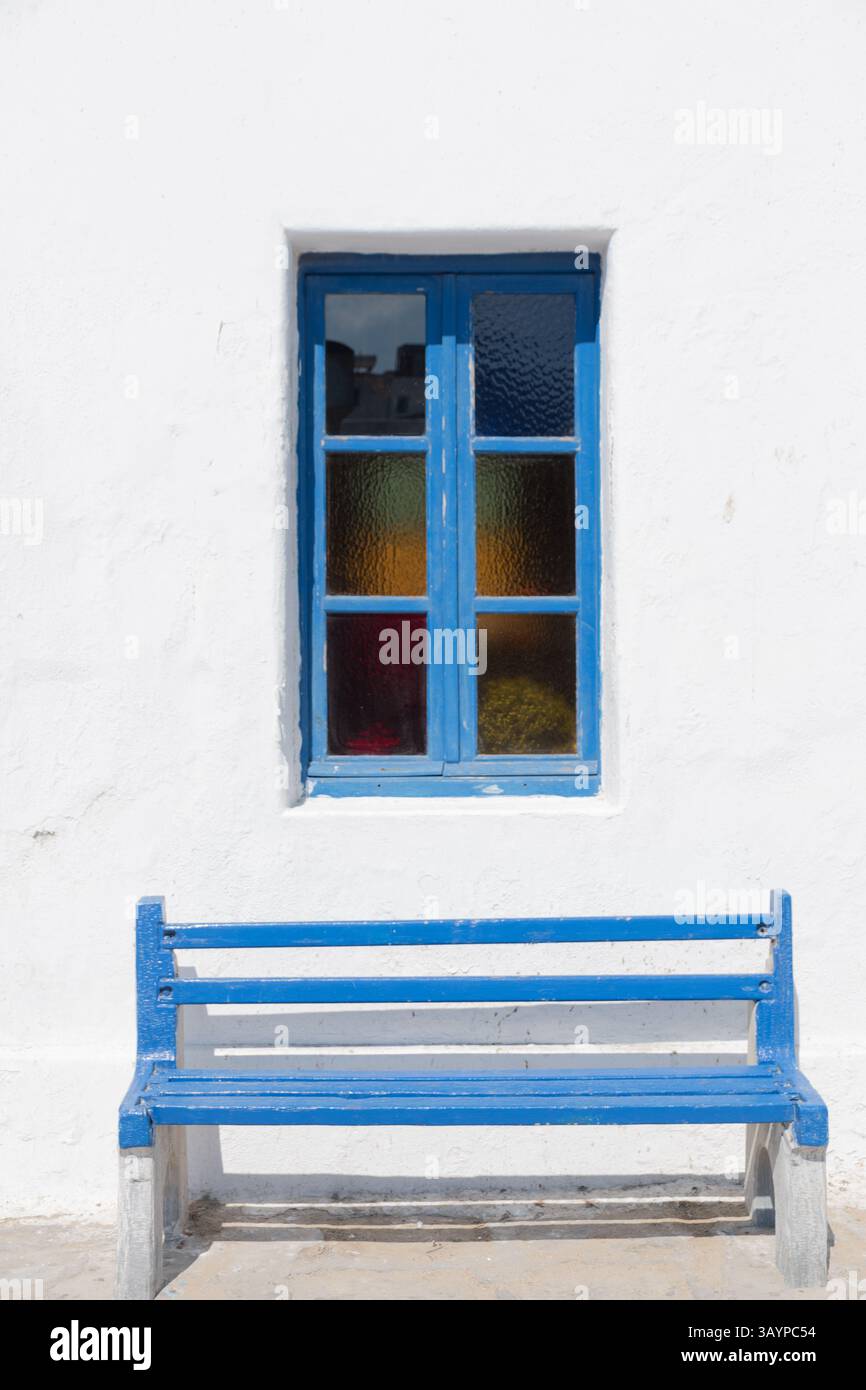 White washed building with window and a bench in front of it in blue ...