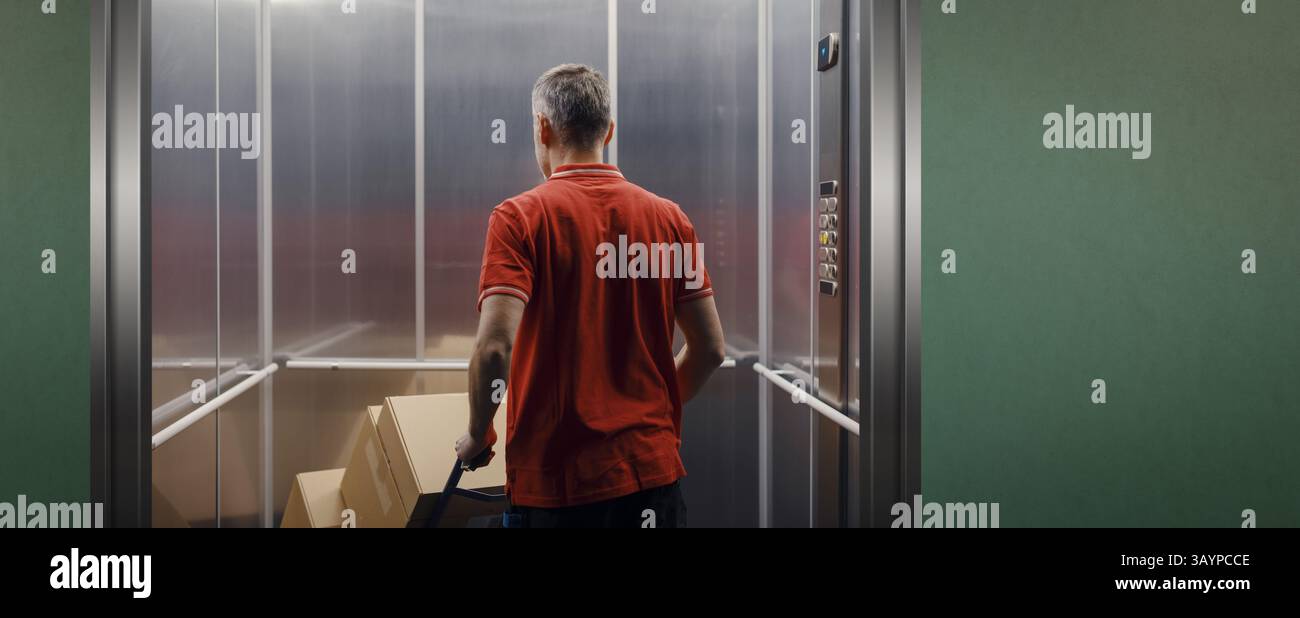 Delivery man getting in the elevator and pushing a hand truck loaded ...