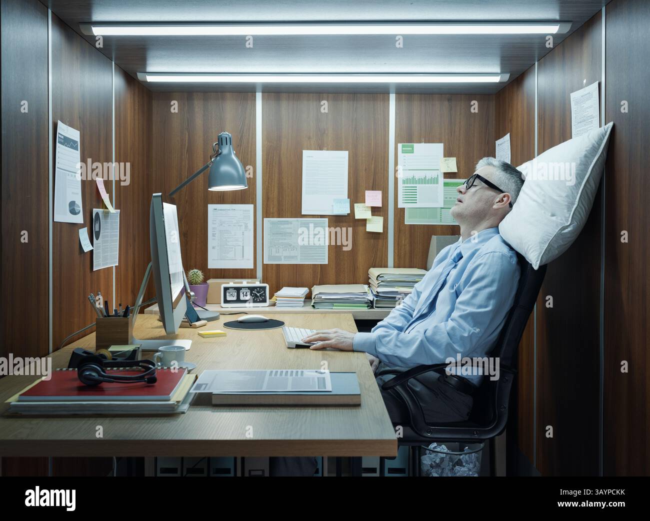 Tired corporate business employee sleeping at his desk in a small ...