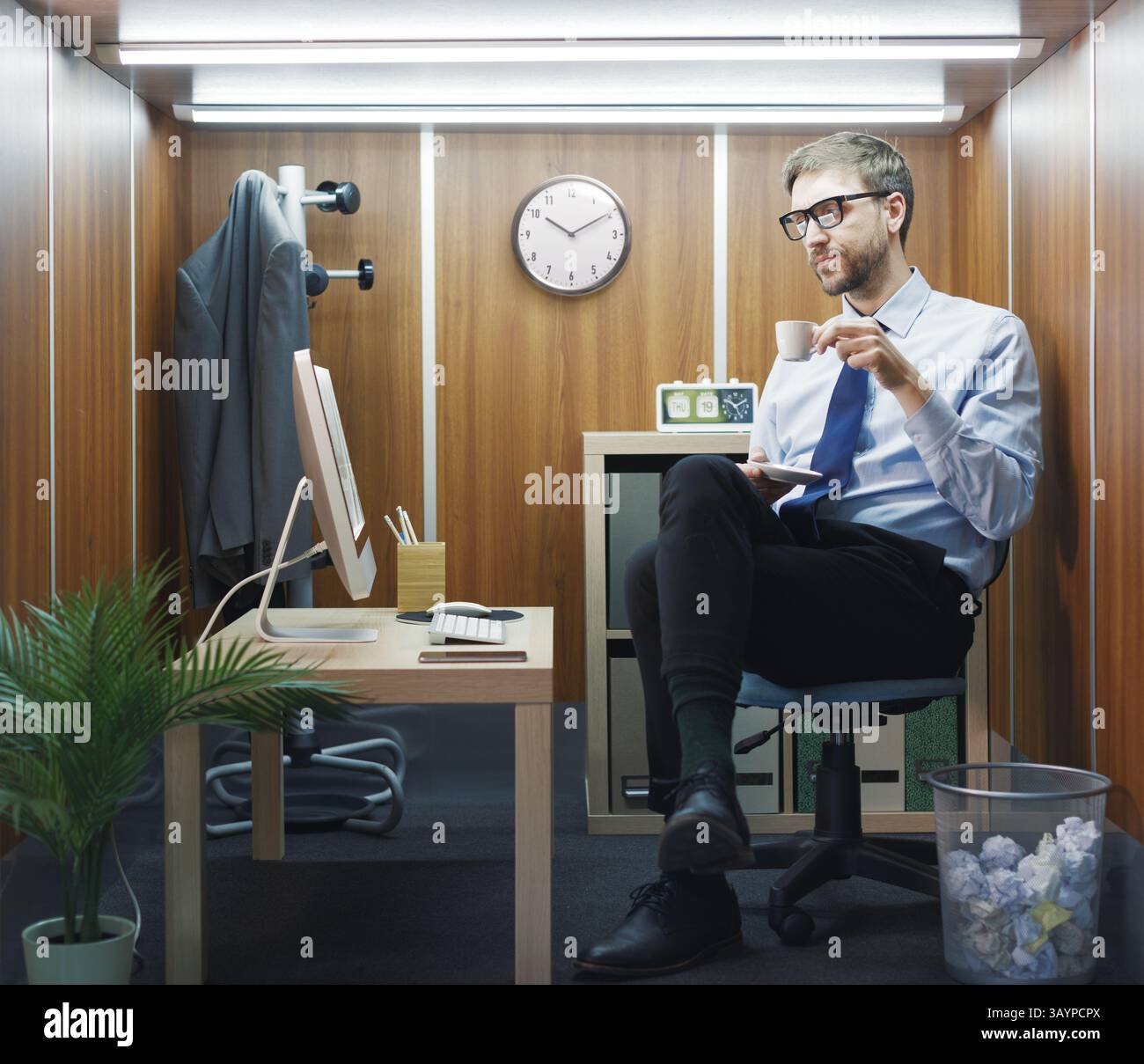 Corporate businessman having a coffee break in his tiny office, lack of ...