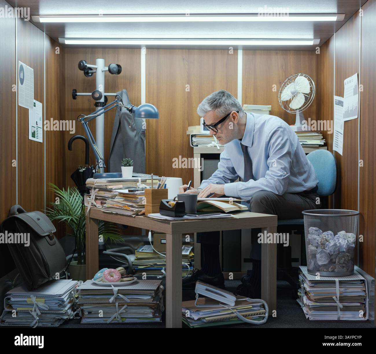 Efficient employee sitting at his desk and working in a small office ...