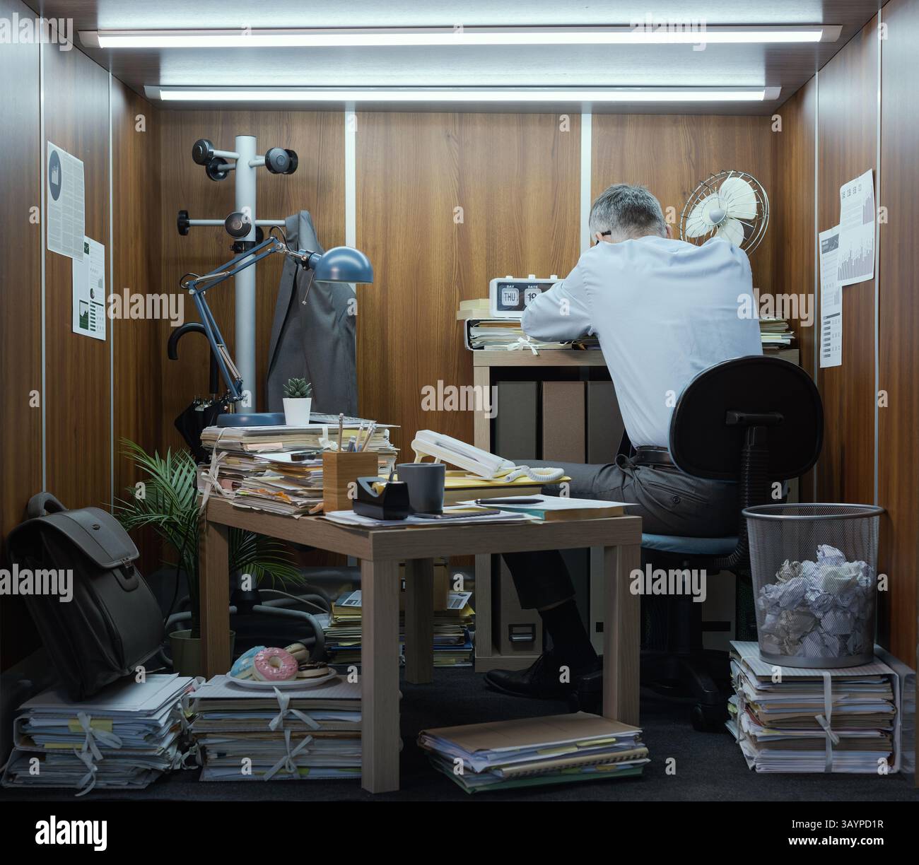 Frustrated hopeless businessman working in a small cheap messy office ...