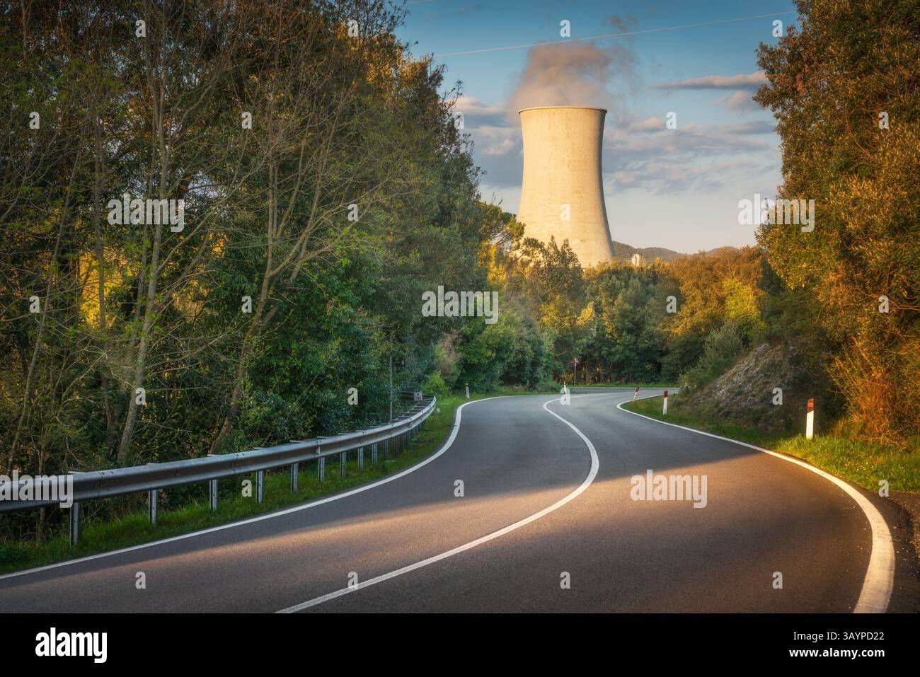 Cooling towers in geothermal power plant and a winding road at sunset ...