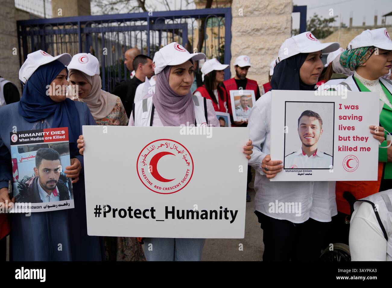 Paramedics from the Palestine Red Crescent Society, PRCS, hold signs to ...