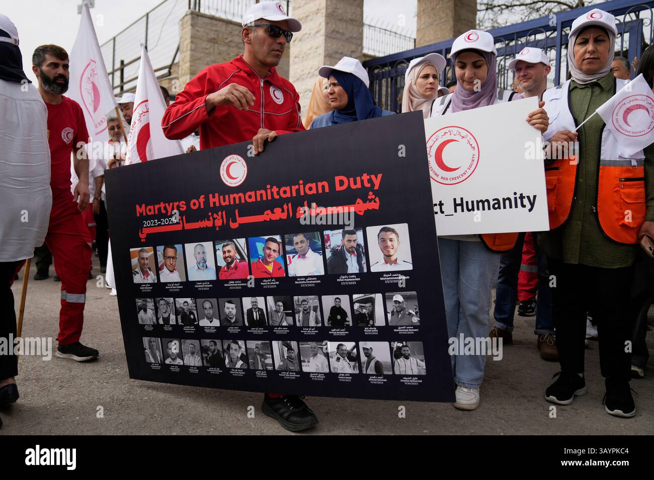 Paramedics from the Palestine Red Crescent Society, PRCS, hold signs to ...
