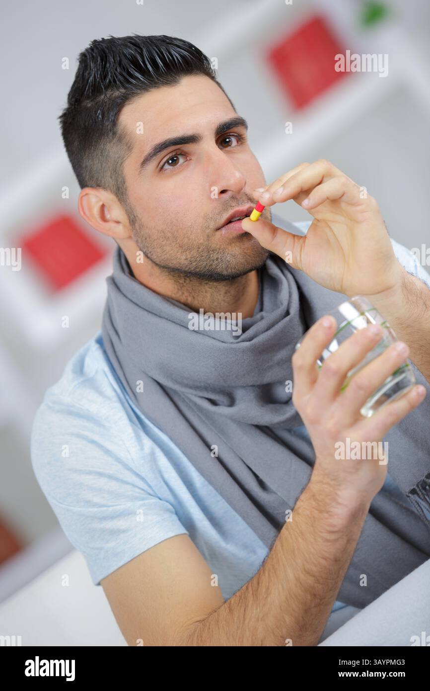young man wearing scarf taking medication in tablet form Stock Photo ...