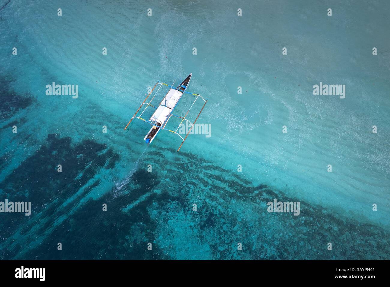 Traditional fishing boat at the coast of the shallow tropical sea at the coast of Morotai island ...