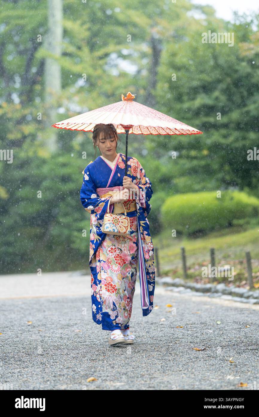 A local city in Japan on a rainy summer day. Japanese woman wearing a ...