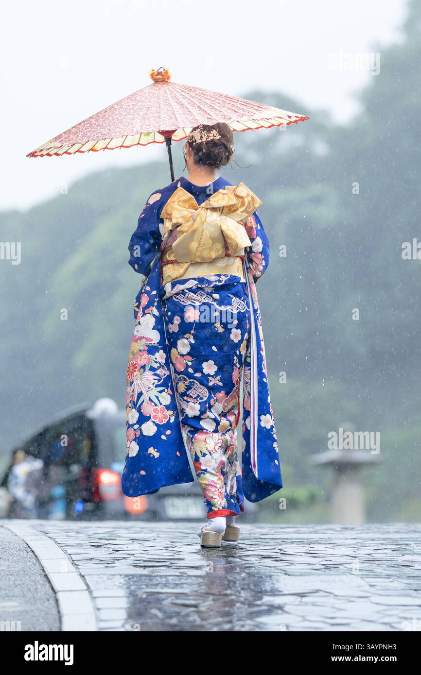 A local city in Japan on a rainy summer day. A Japanese woman wearing a ...