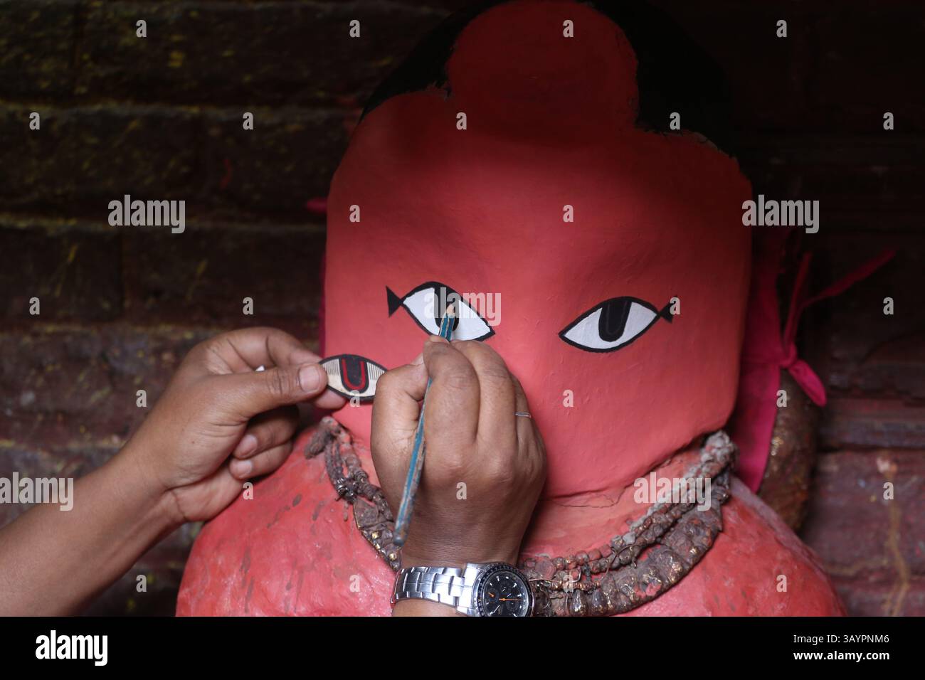 A priest applies the final touch of paint to the statue of the idol ...