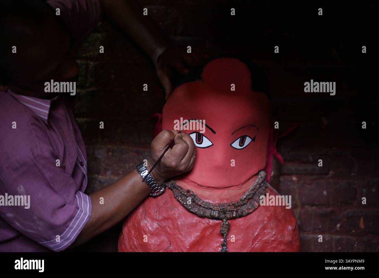 A priest applies the final touch of paint to the statue of the idol ...