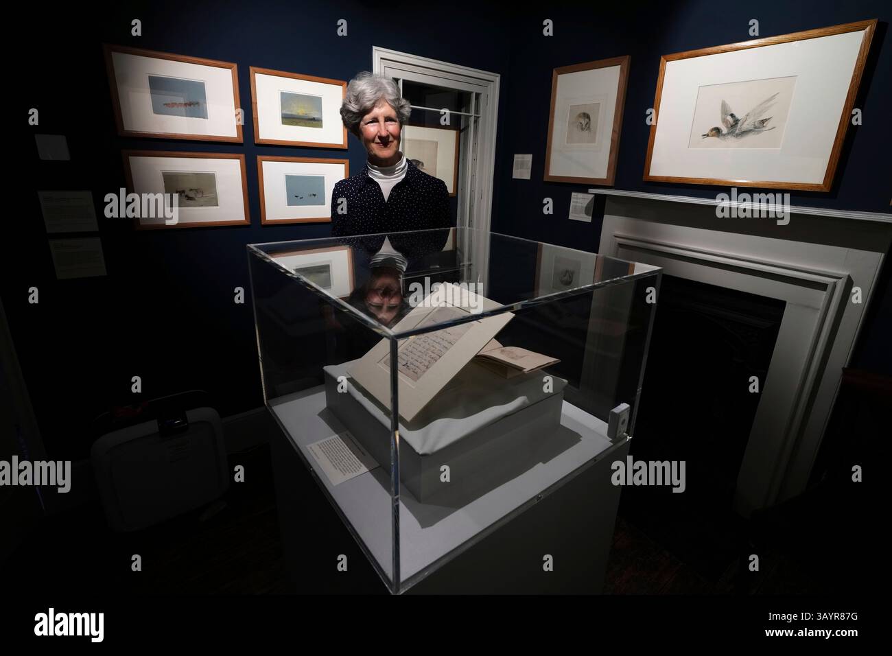 A volunteer looks towards paintings in the exhibition called Turner's ...