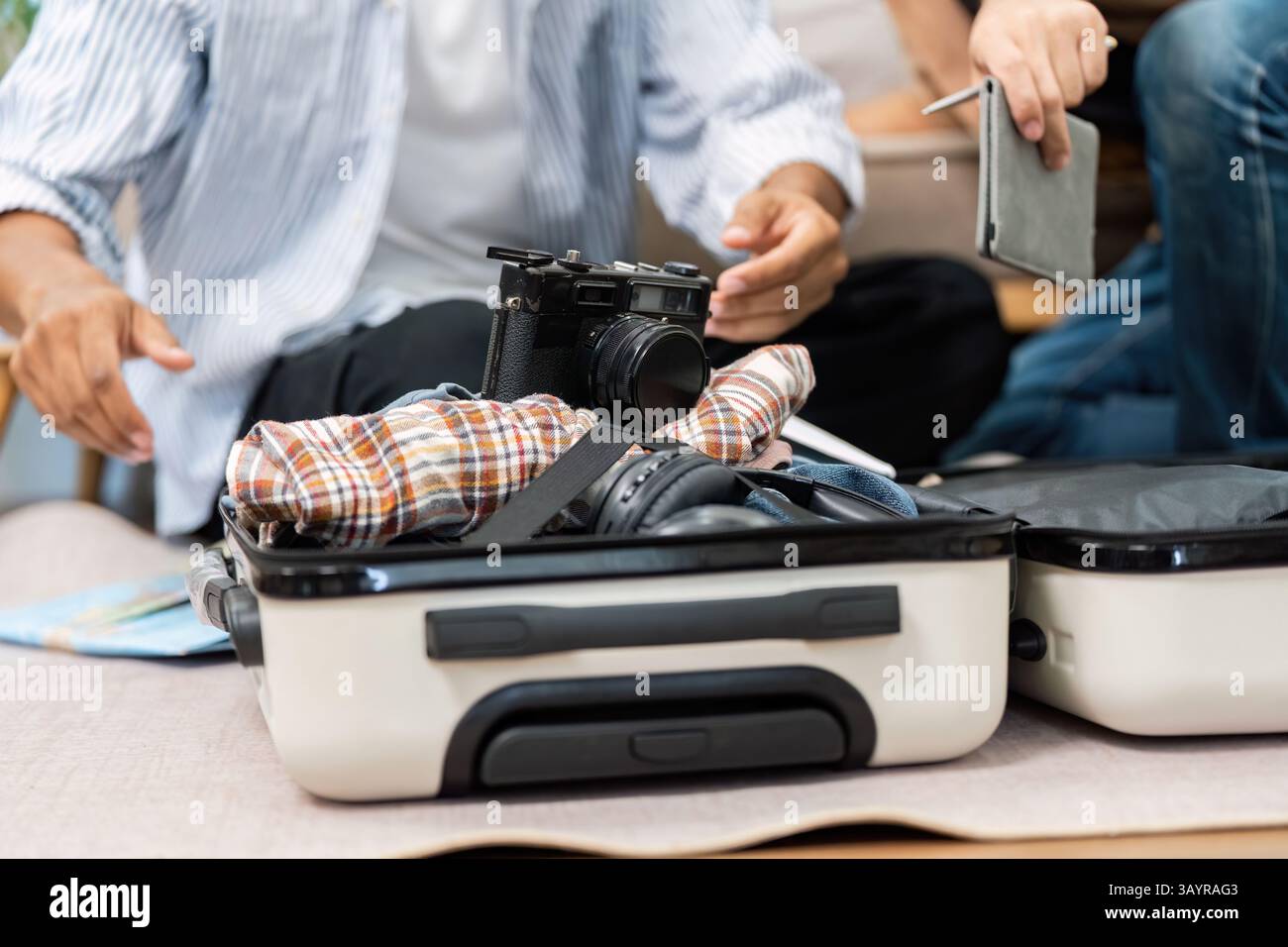 Essentials for a Journey. A couple packing their suitcase with travel ...