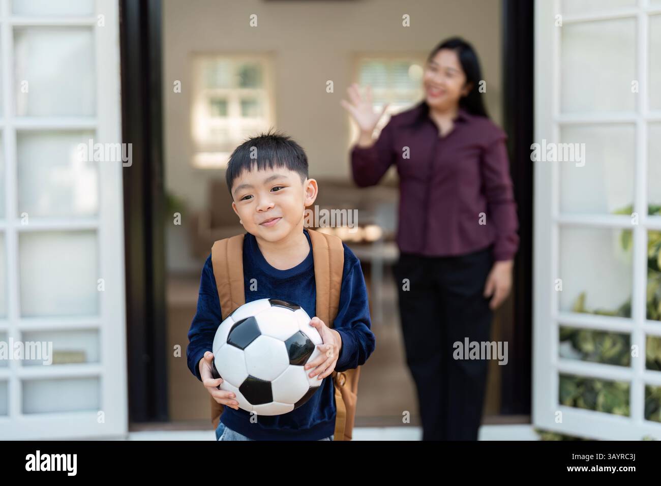 Back to School Excitement and Family Support. A boy holding a soccer ...