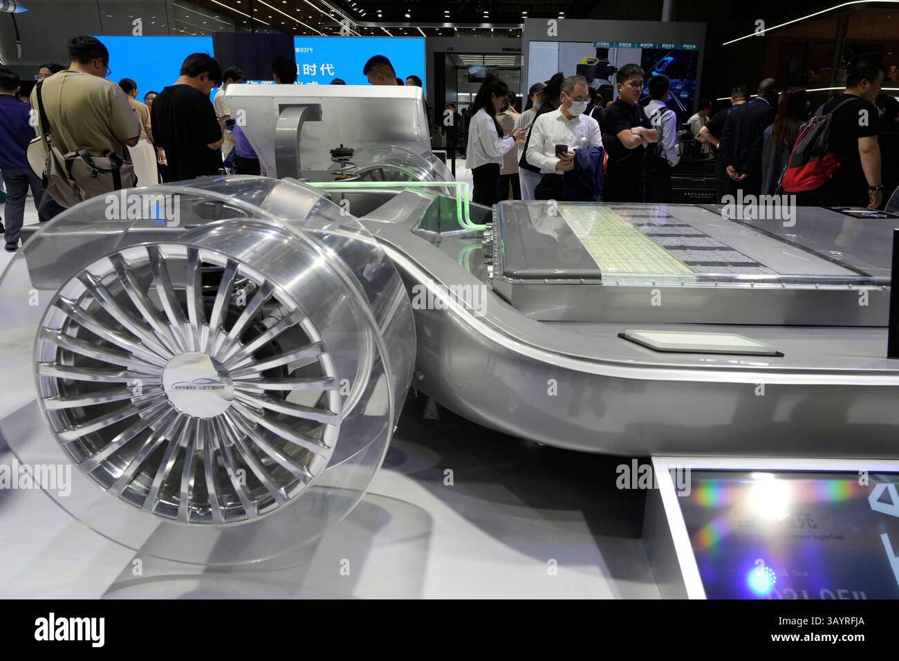 Visitors look at the fast charging battery from CATL that promises ...