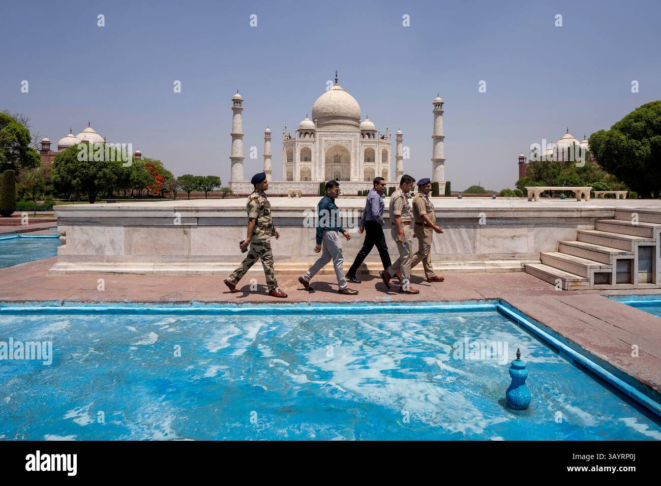 Security officers walk with the Taj Mahal in the background in Agra ...