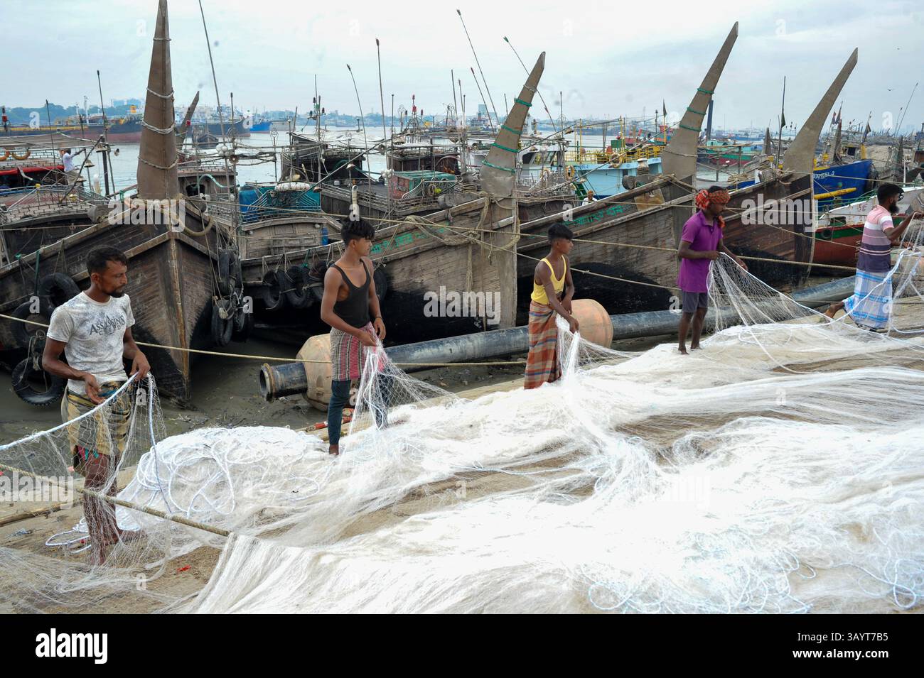 Fishermen are busy repairing fishing nets on the banks of the ...