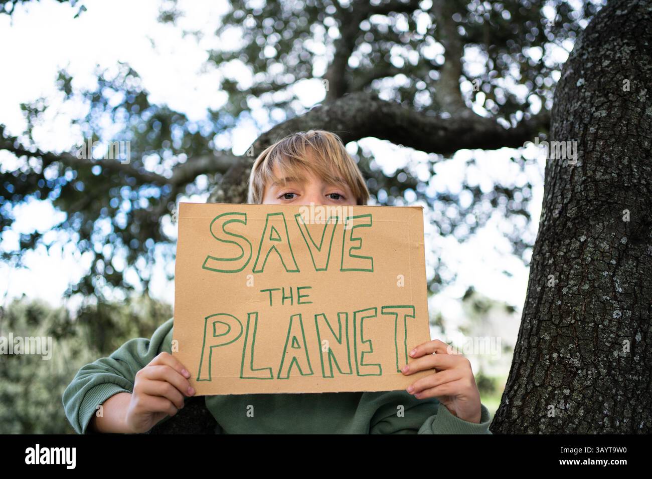 Child holding a cardboard poster with the message save the planet ...