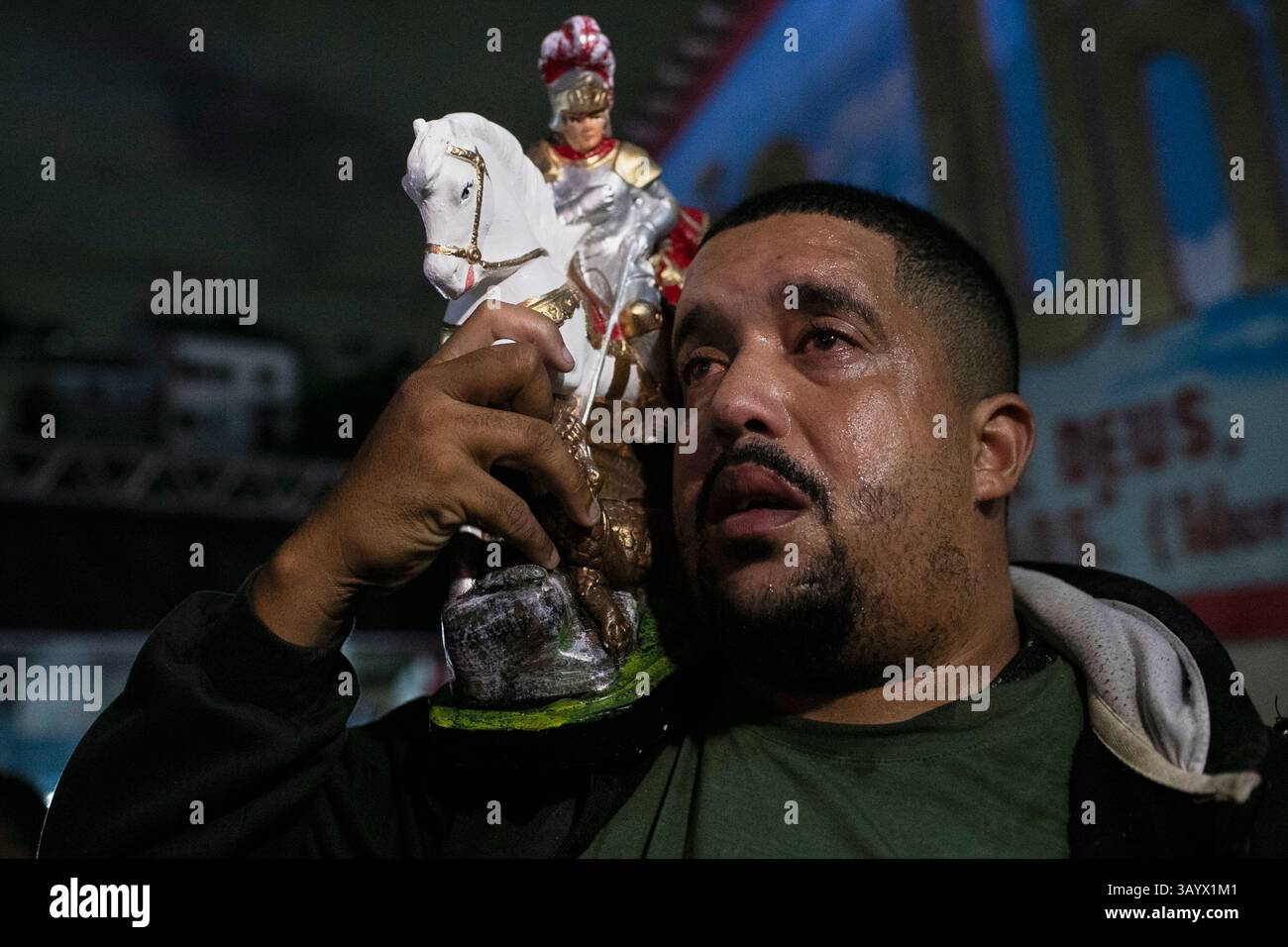 Gledson Bezerra da Silva, 39, cries while holding a statue of Saint ...
